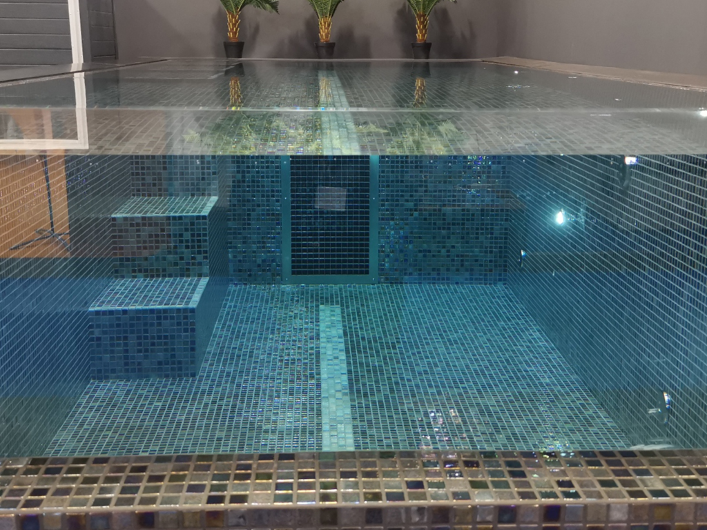 Mosaic swim spa with glass wall overflow